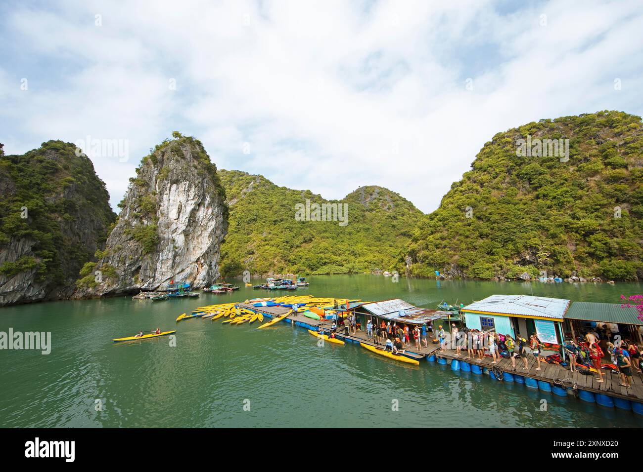 Holidaymakers queue for a kayak on a jetty, behind the karst rocks in ...