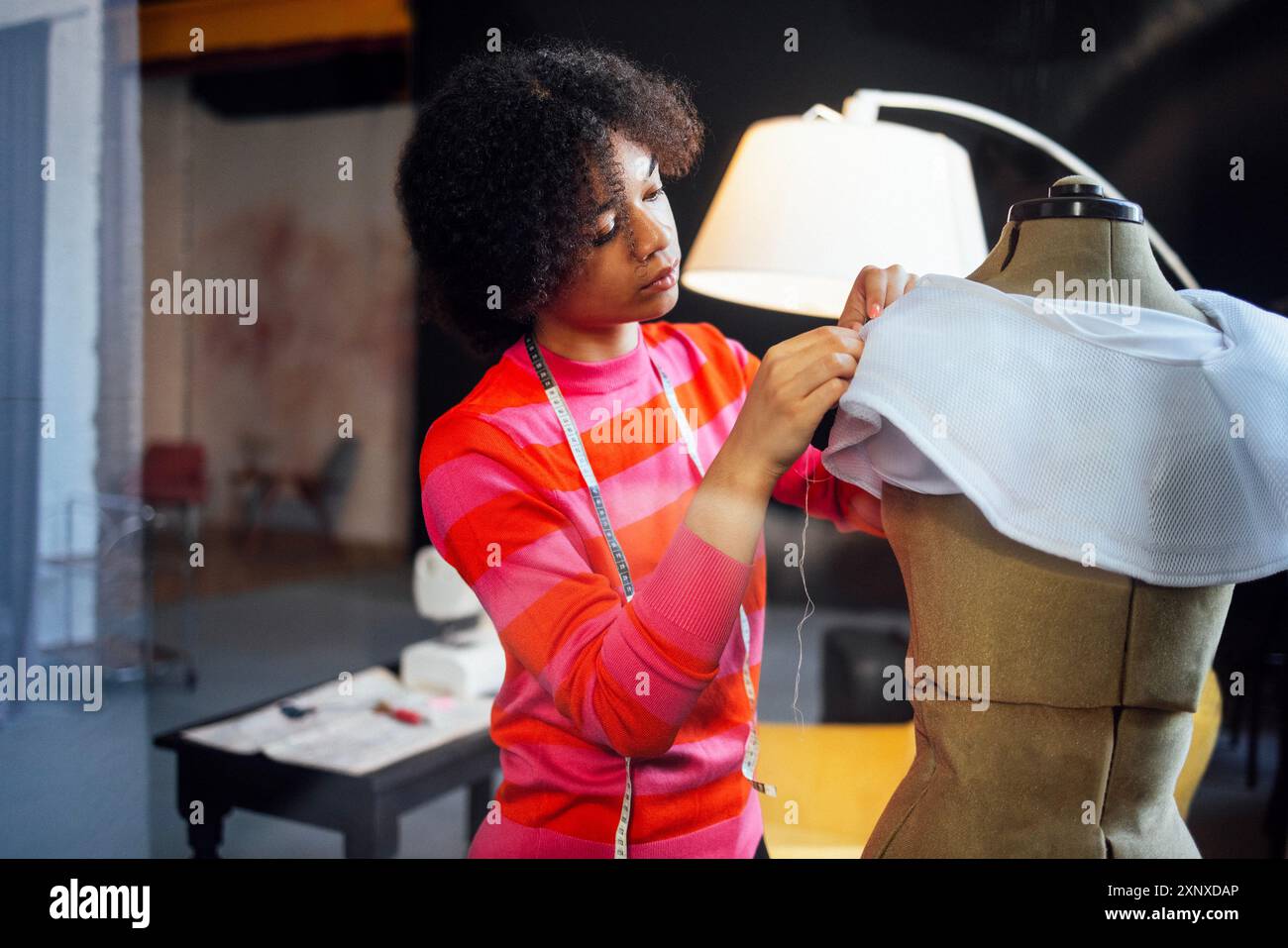 A young African stands next to a dressmaker mannequin. A seamstress ...
