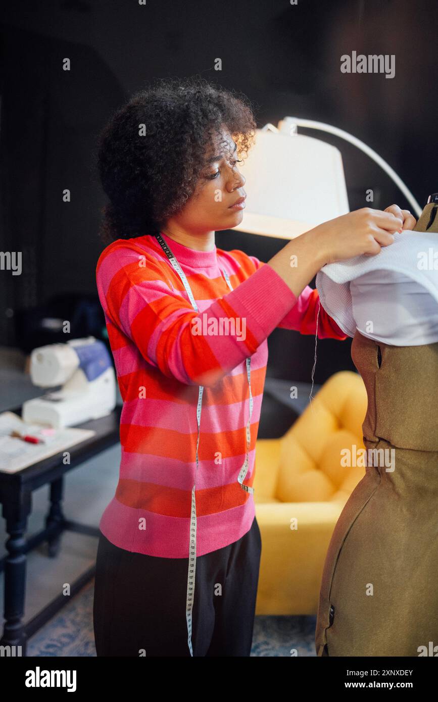 A young African stands next to a dressmaker mannequin. A seamstress ...