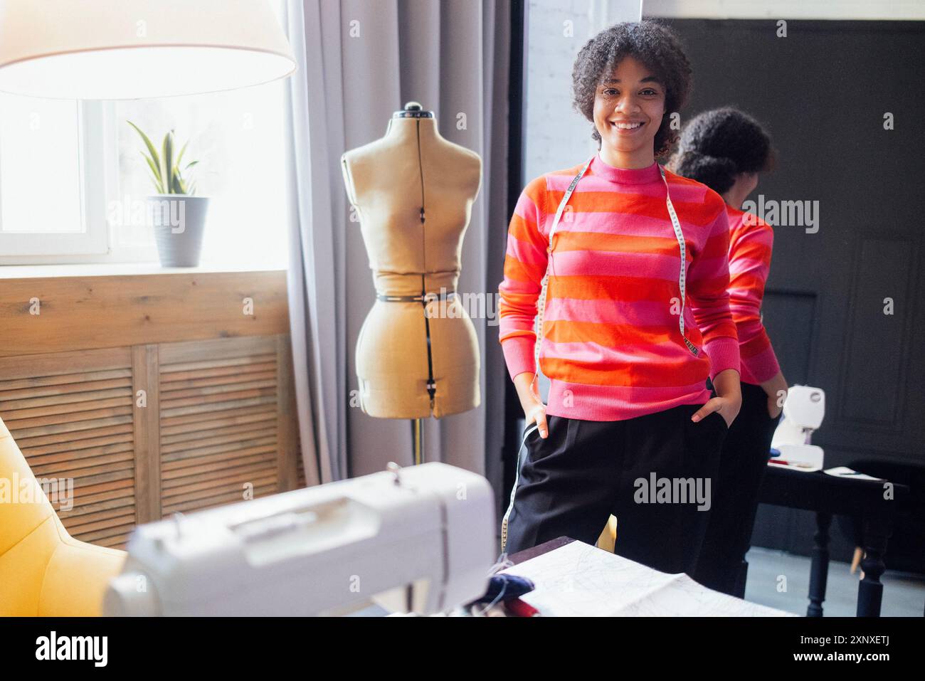 Young laughing African woman stands next to dressmaker mannequin ...