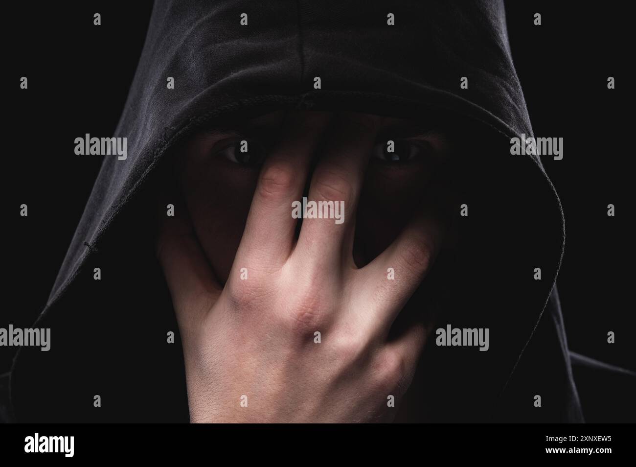 A low key portrait of a man in a hooded hand gesture makes a sperm hero ...