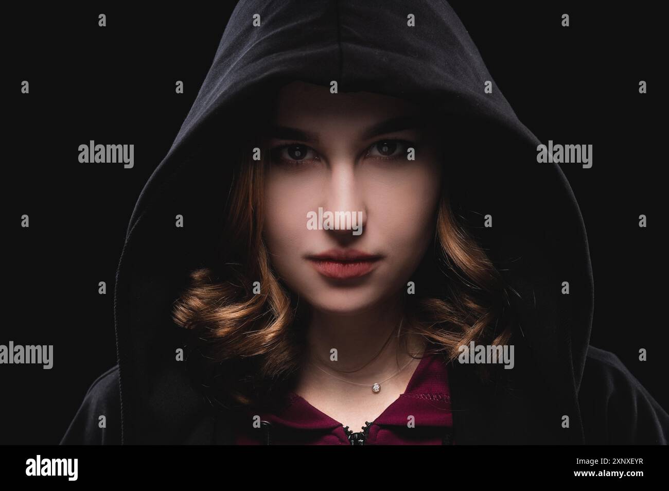 Close-up portrait of a secretive young girl in a deep dark hood on a ...