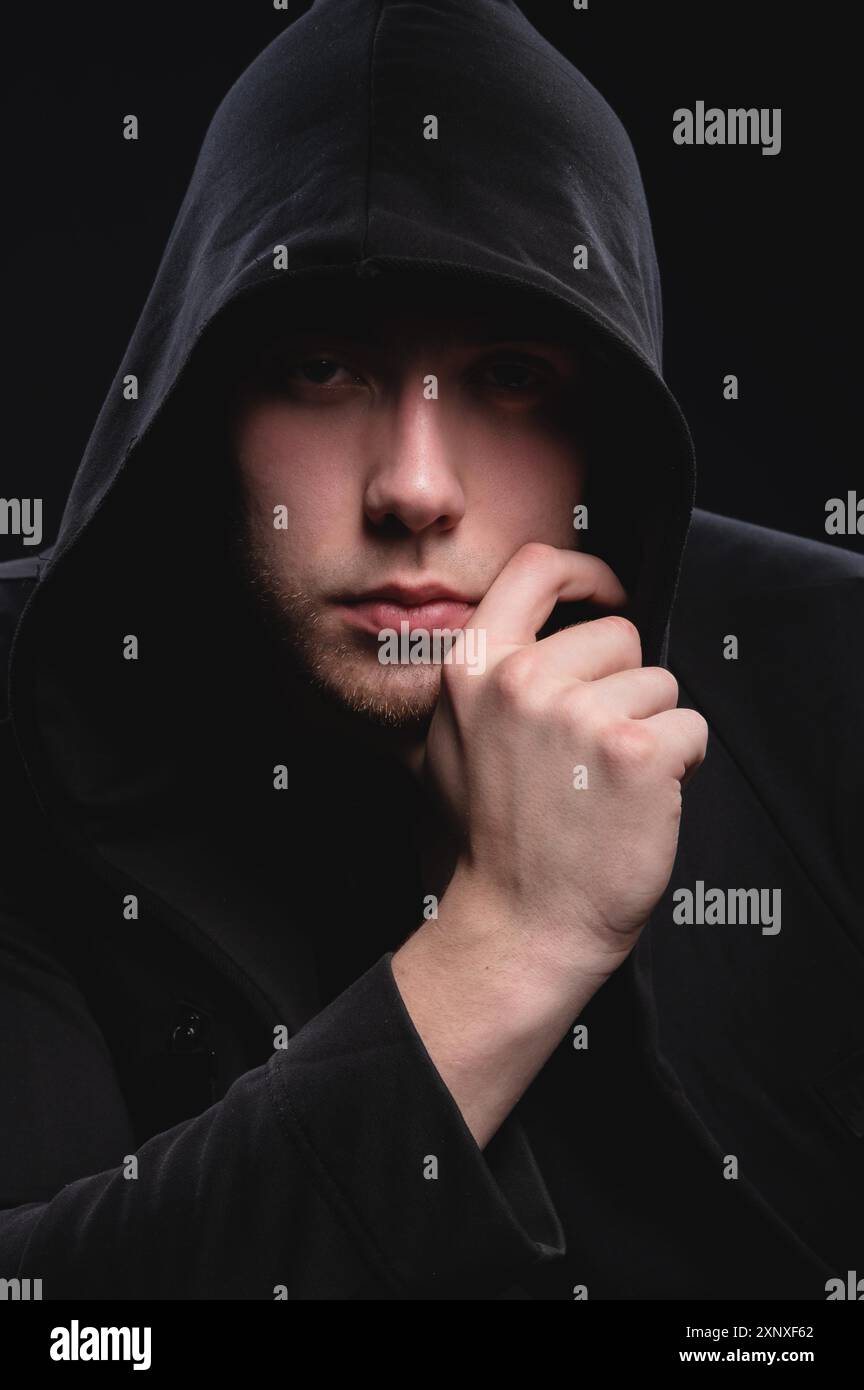 A low key portrait of a man in a hooded hand gesture makes a sperm hero ...