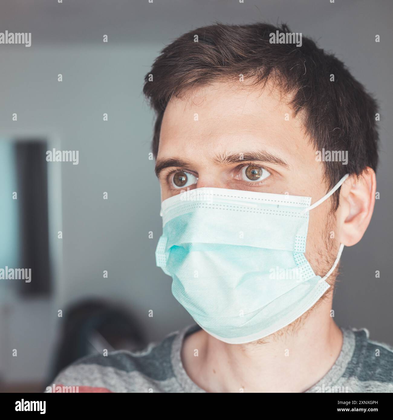 Young man indoor wearing a face mask, portrait. Corona and flu season ...