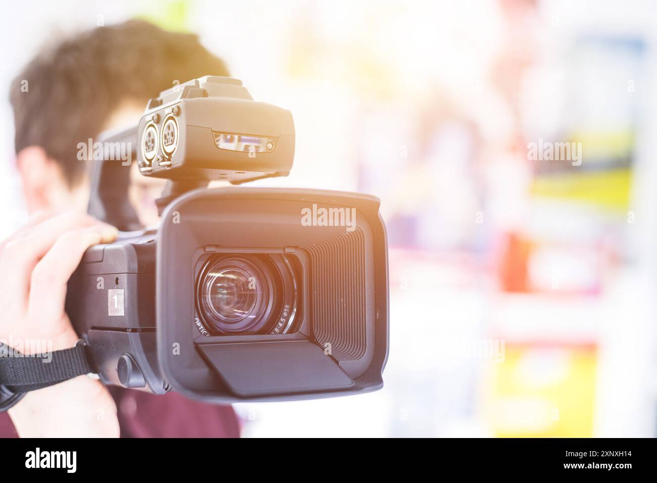 Male cameraman is holding a professional video camcorder, blurry ...