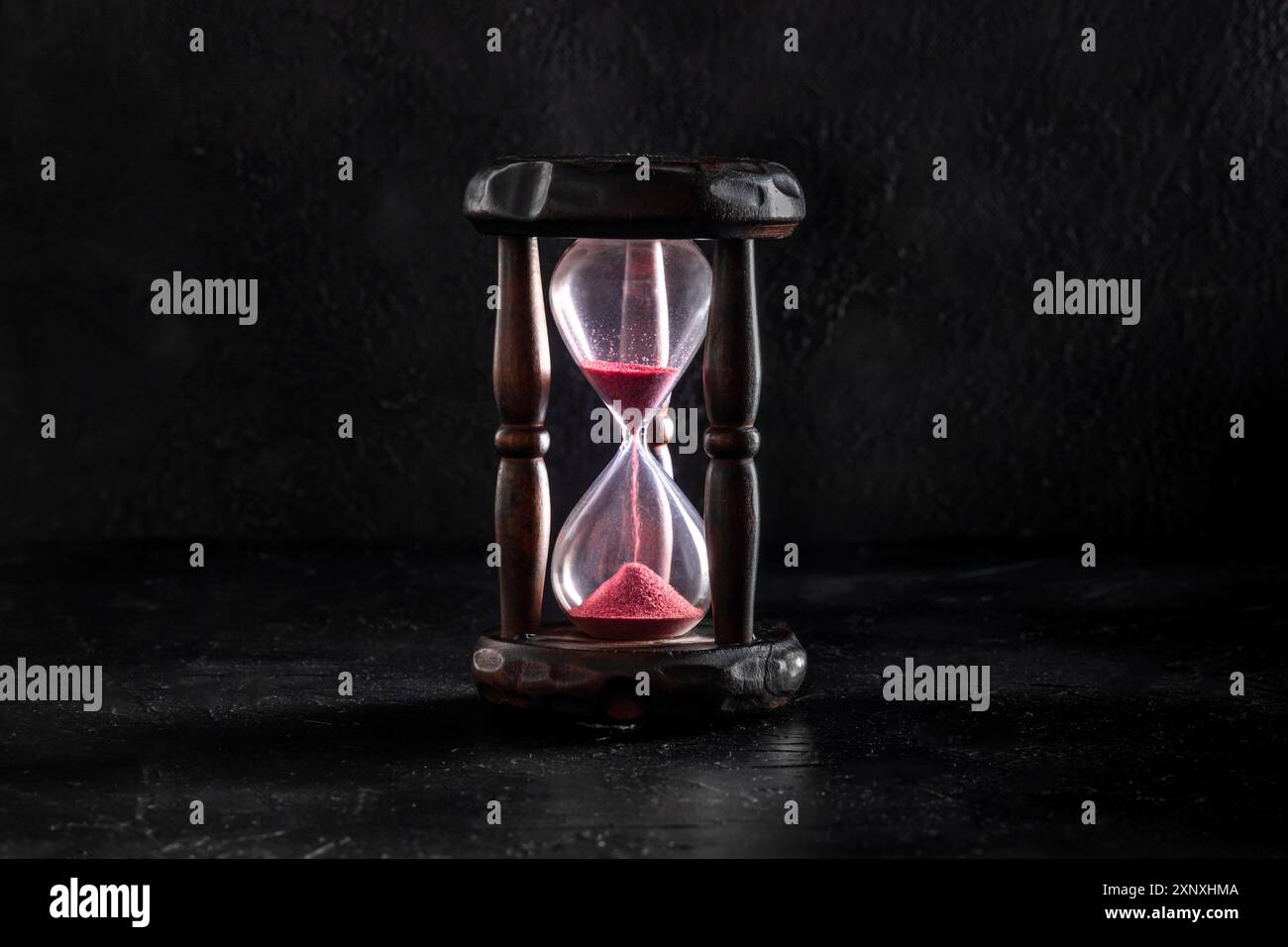 Time management concept. A vintage hourglass on black, a side view ...