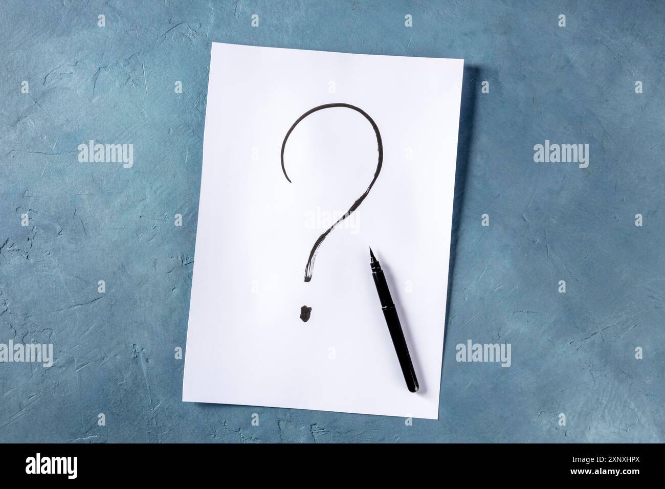 Question mark, written in ink on a piece of standard office paper, shot ...