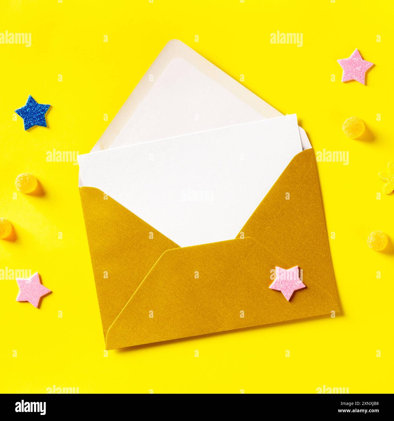 A white greeting card in a golden envelope, overhead square shot on a ...