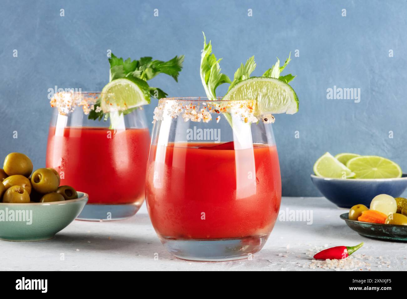 Bloody Mary cocktails, garnished with lime and celery, with olives and ...