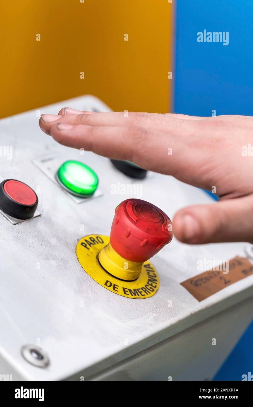 Hand pressing the red emergency button or stop button for industrial ...