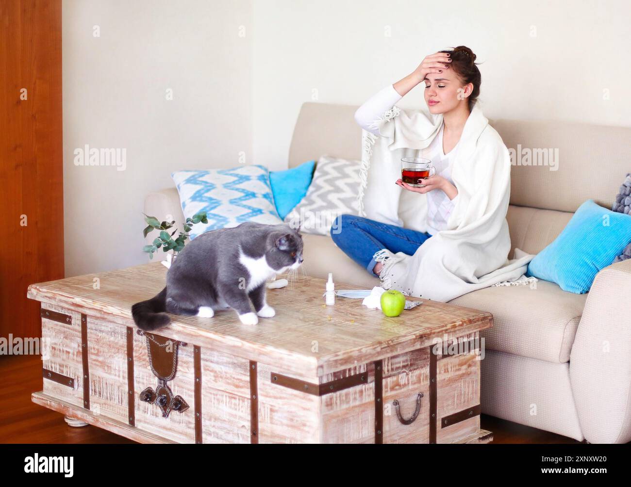 Ill female with cup of hot tea touching forehead with closed eyes while ...