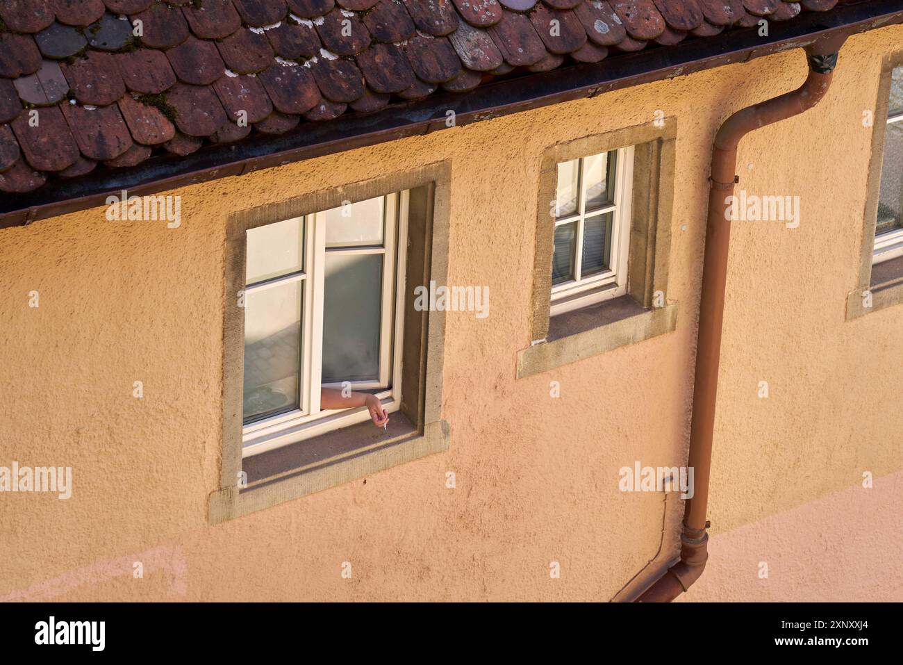 Smoking through an Open Window. The hand of a smoker with a lit ...