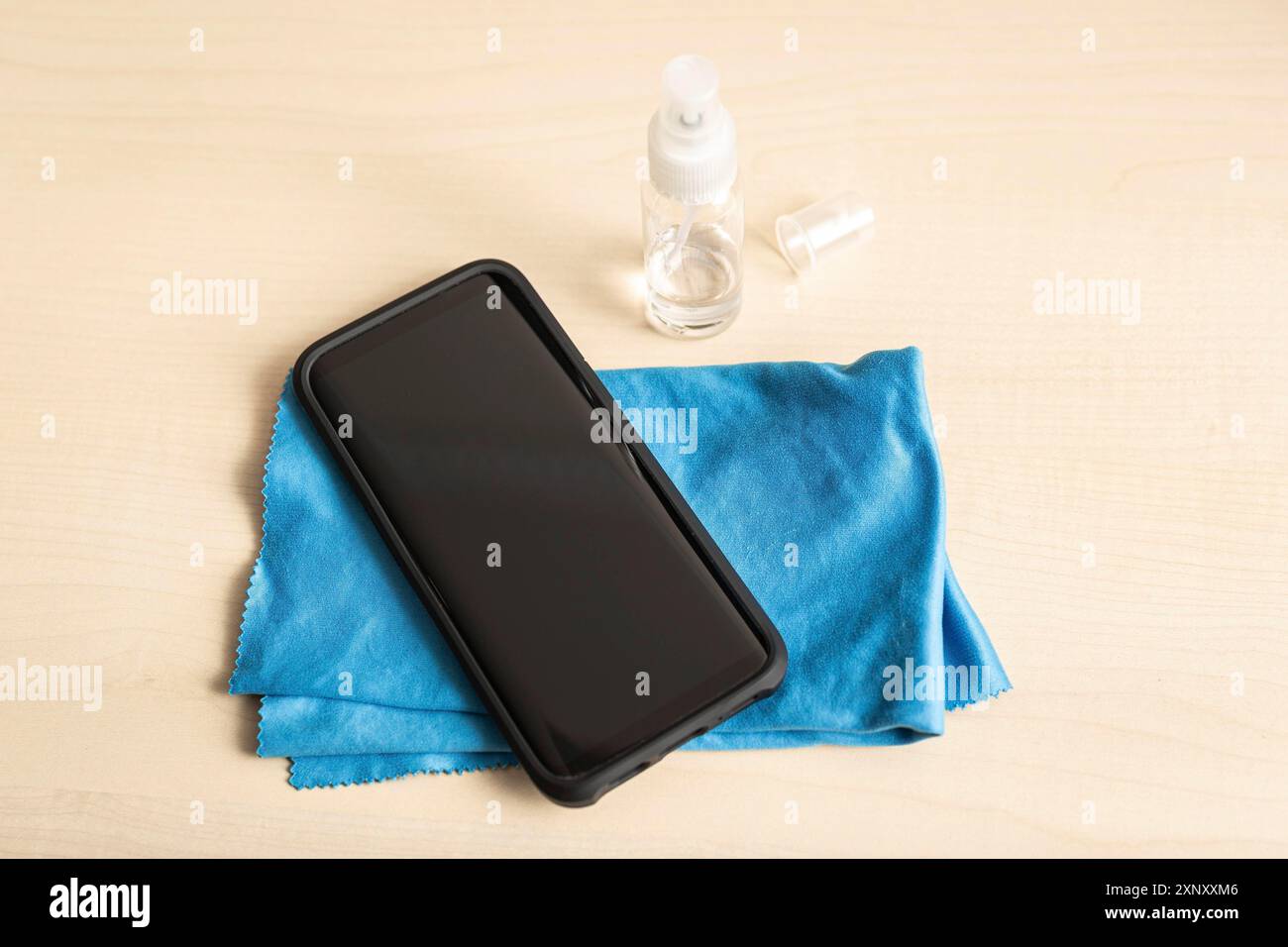 Mobile phone, cloth and alcohol spray bottle on table. Clean smartphone ...