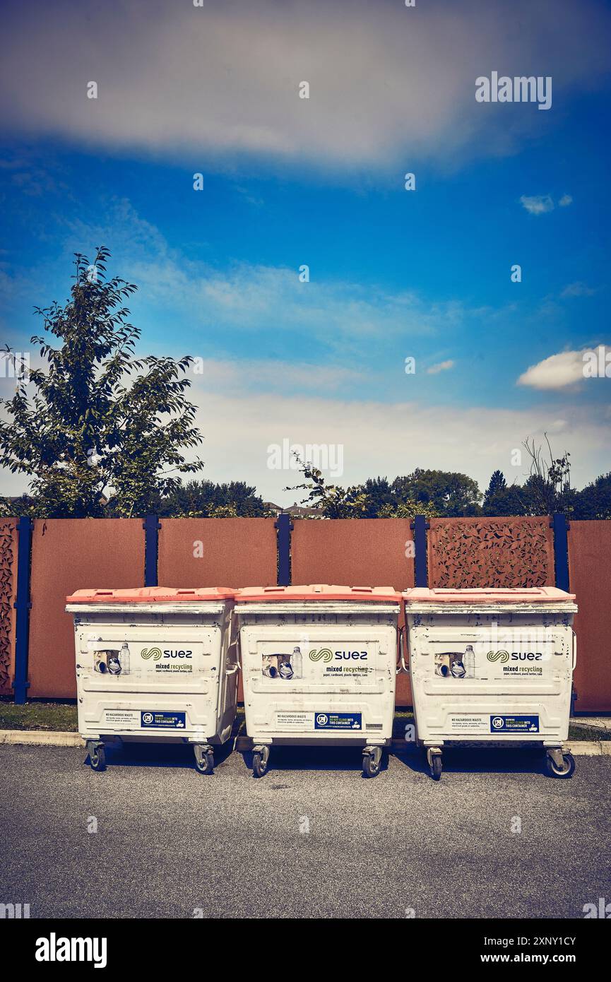 Line of three recycling skips against brown garden fence Stock Photo ...