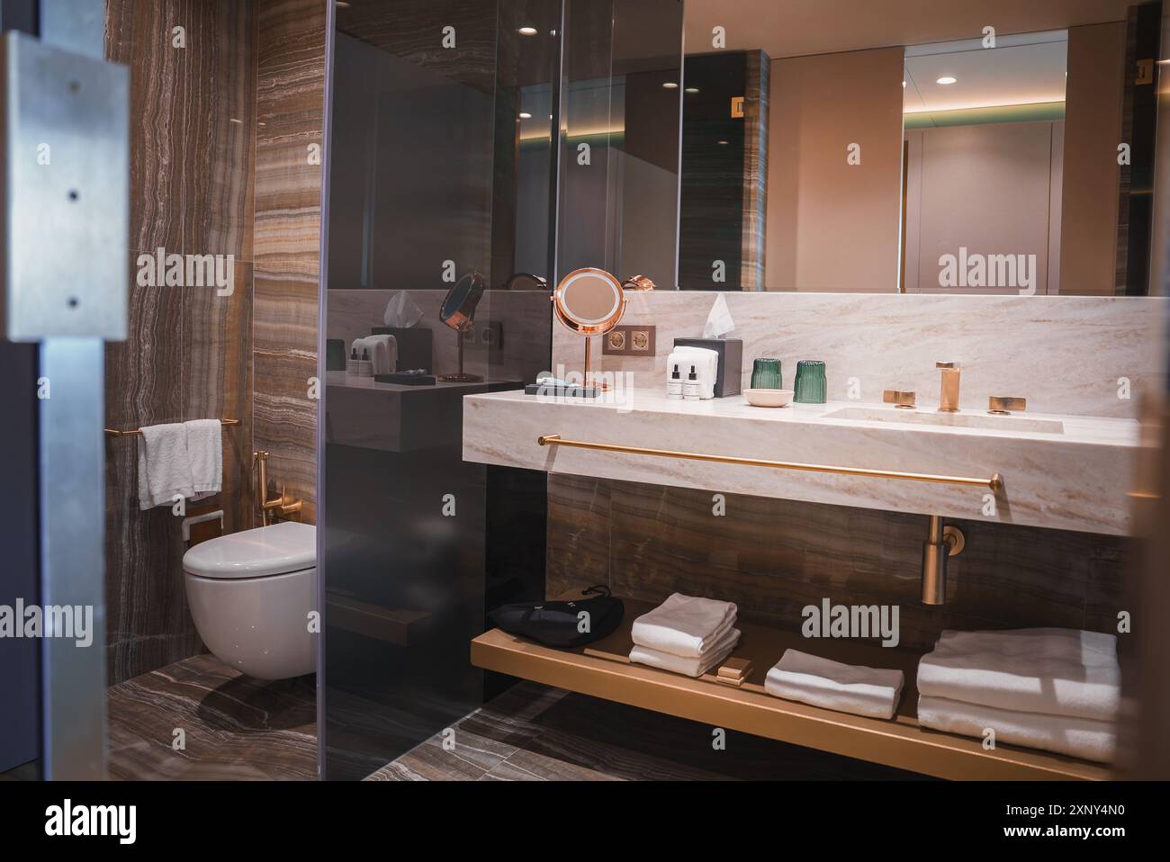 Elegant hotel bathroom featuring a floating marble vanity with gold ...