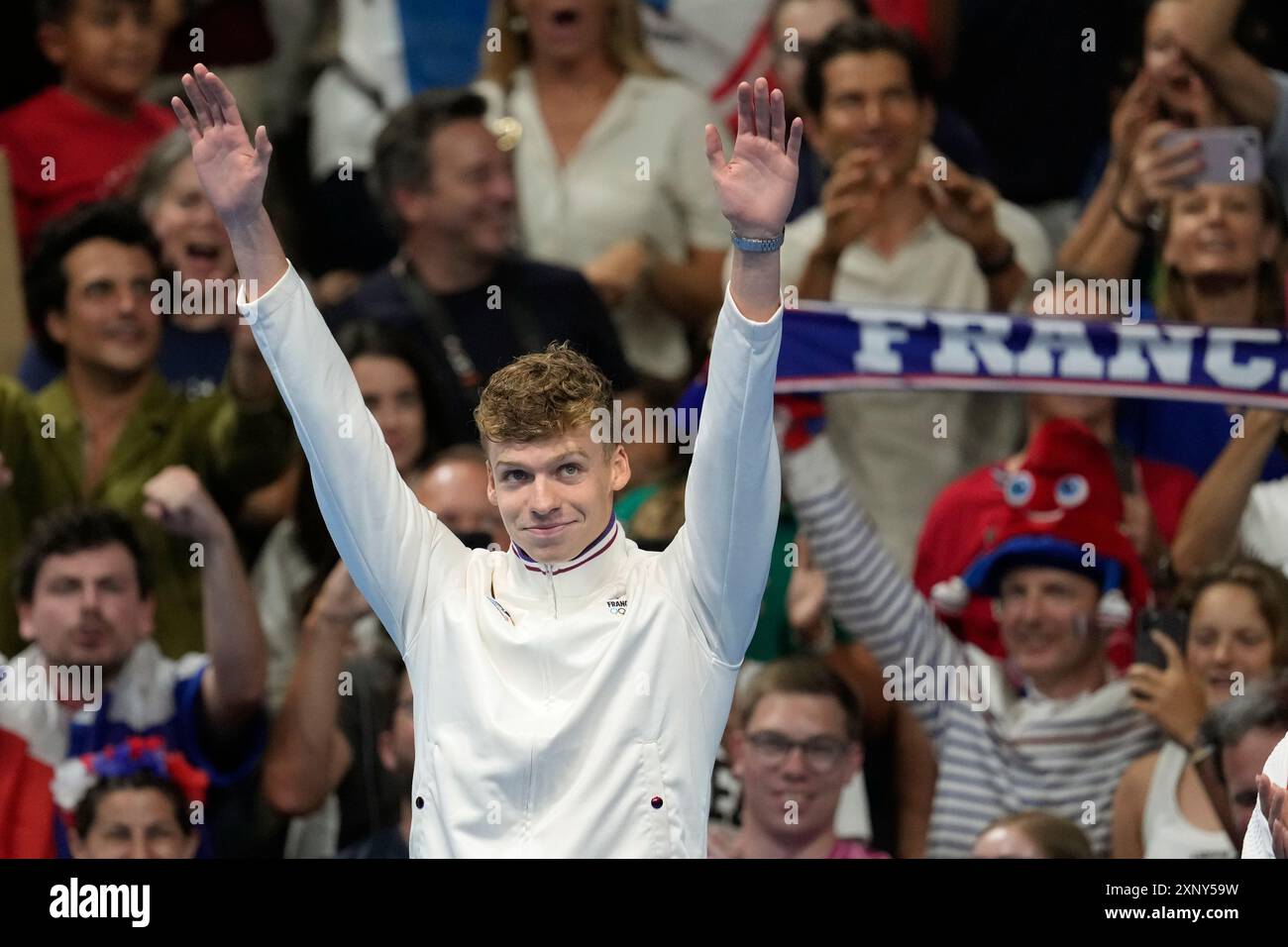 Leon Marchand of France, waves as he stands on the podium to receive ...