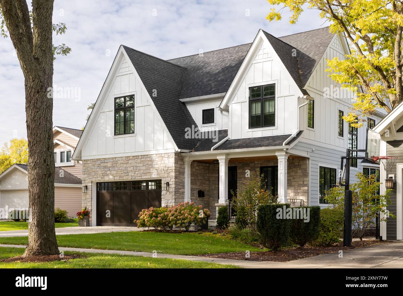 A new, white modern farmhouse with a grey shingled roof and black ...