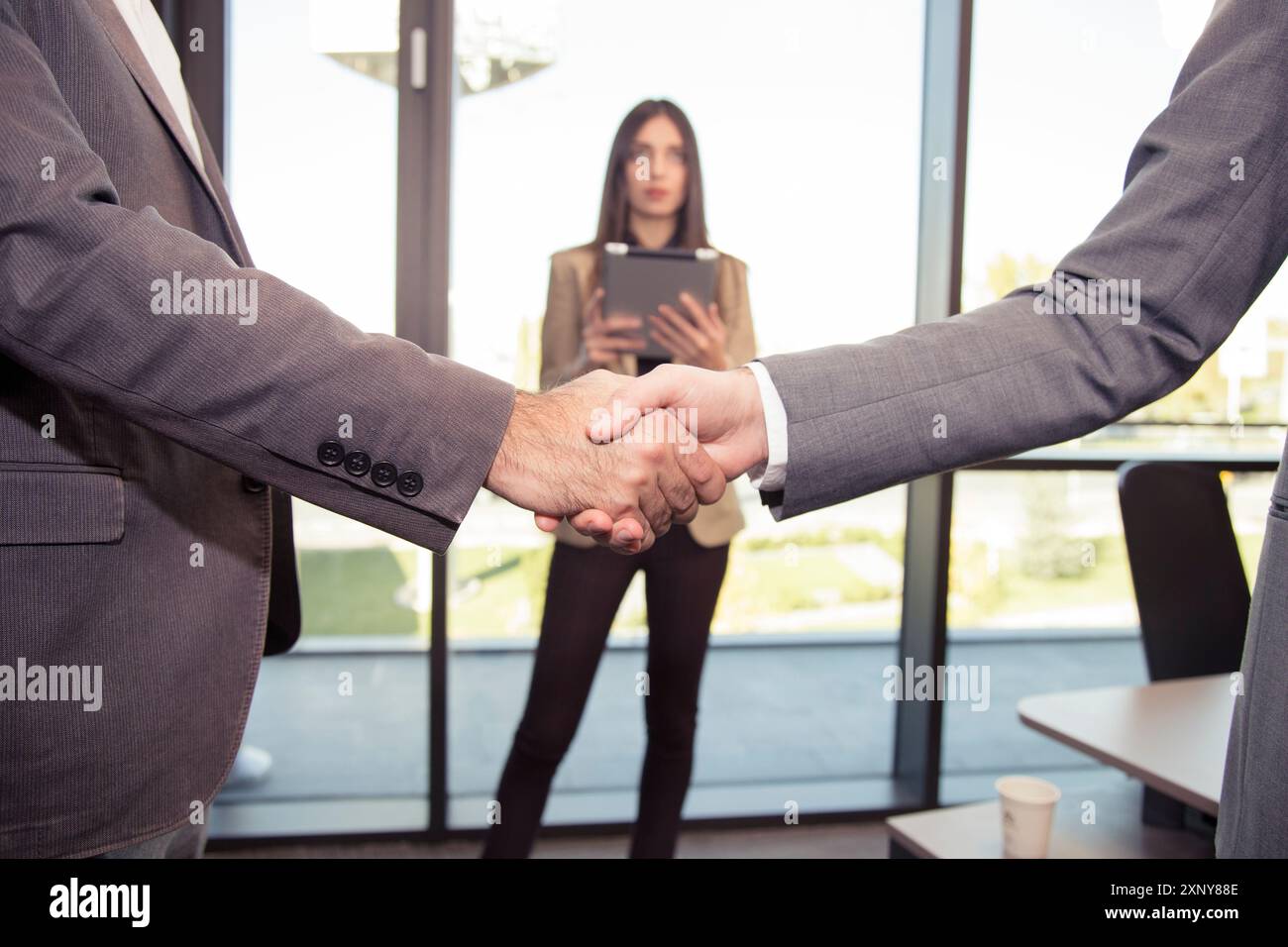 Two men shake hands in front of a woman Stock Photo - Alamy