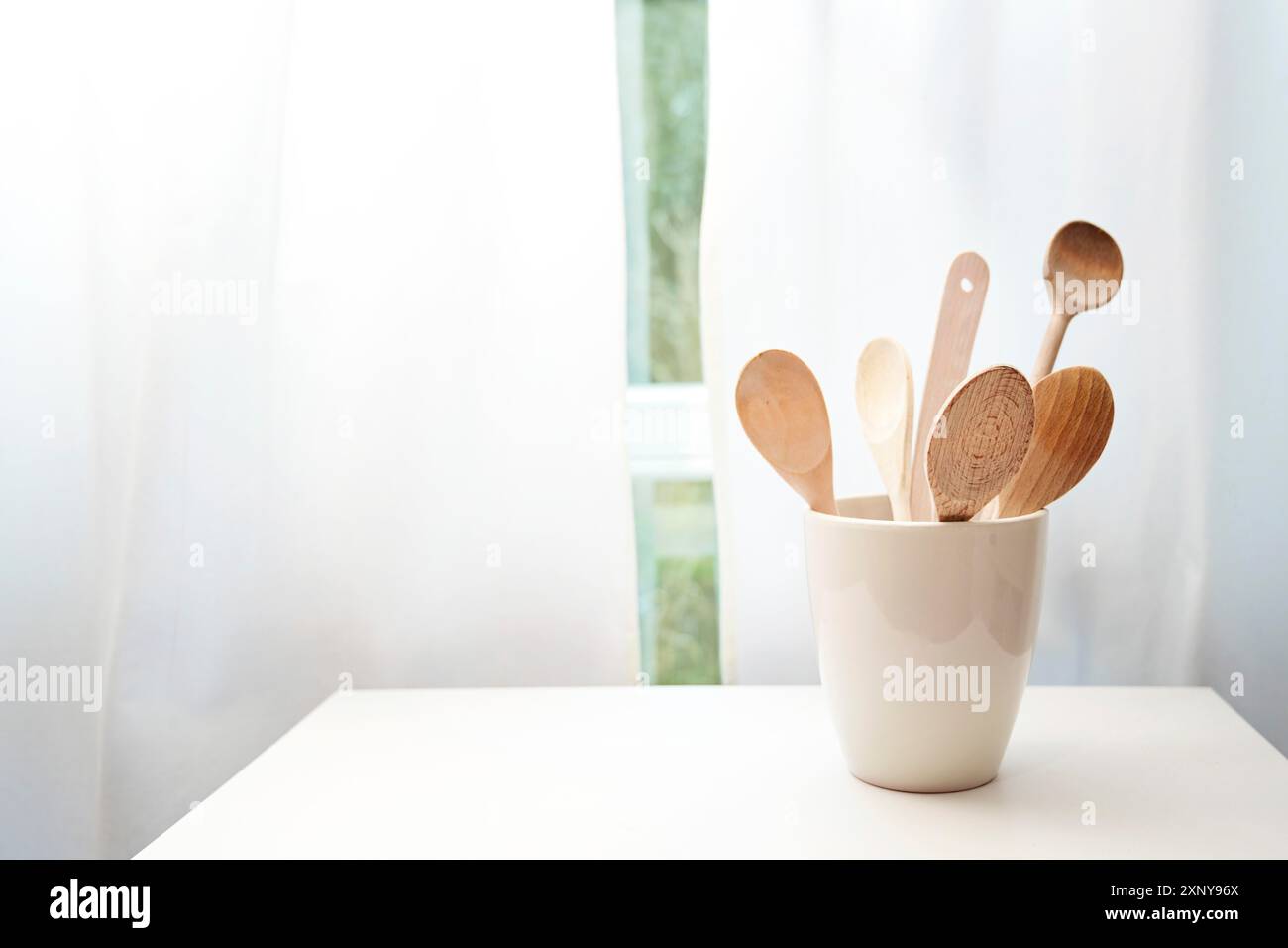 Ceramic pot with wooden cooking spoons on a table in front of the ...