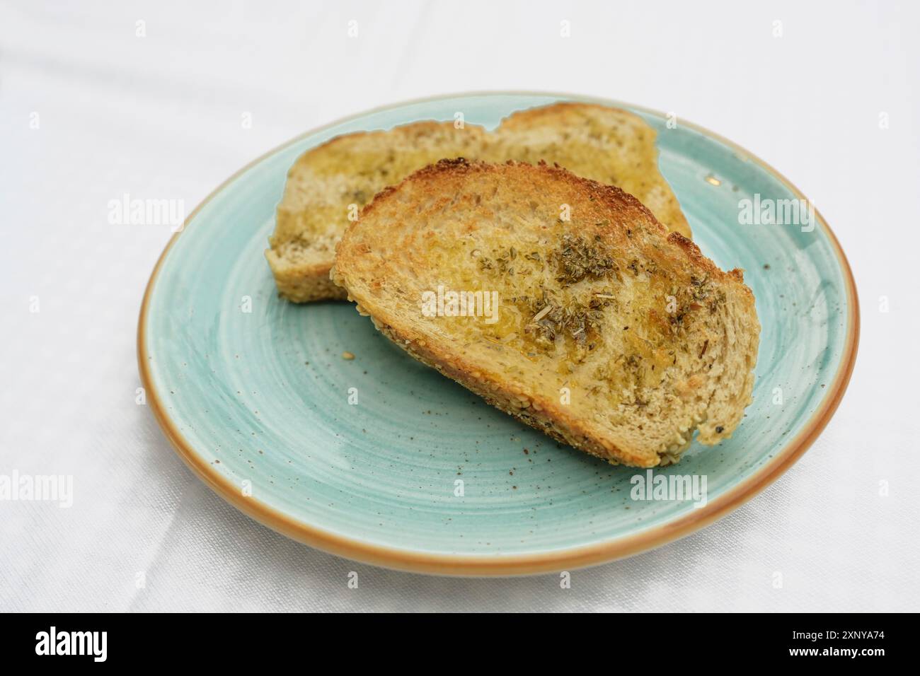 Toasted bread with olive oil, herbs and garlic salt on a blue plate ...
