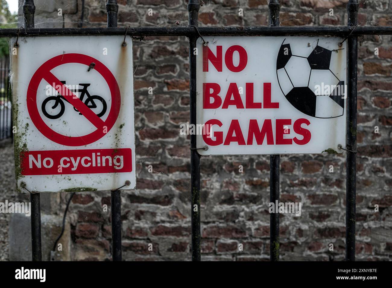 Two prohibition signs on a metal fence, one against cycling and the ...