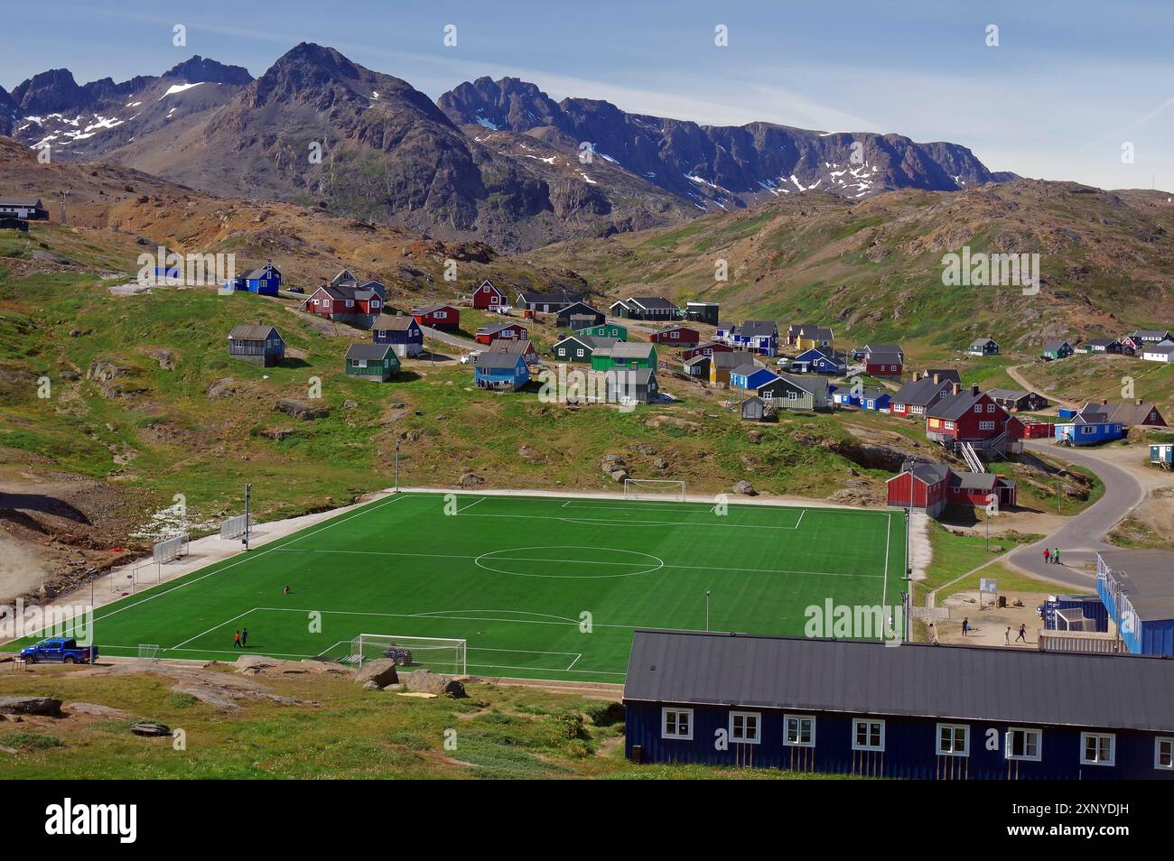 Village with colourful houses and a green football pitch surrounded by ...