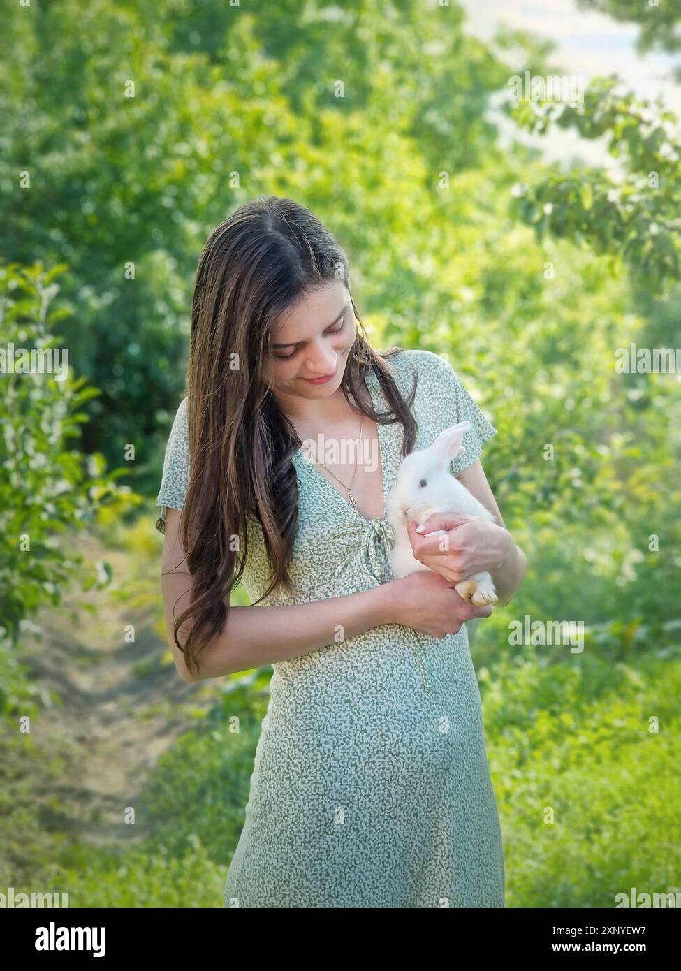 Cute portrait of a young woman holding a white bunny in her arms over a ...