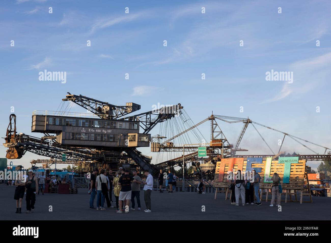 Festival visitors in front of open-cast mining excavator and Melt logo ...