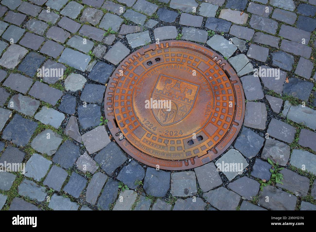 Round rusty manhole cover with city coat of arms and inscription ...