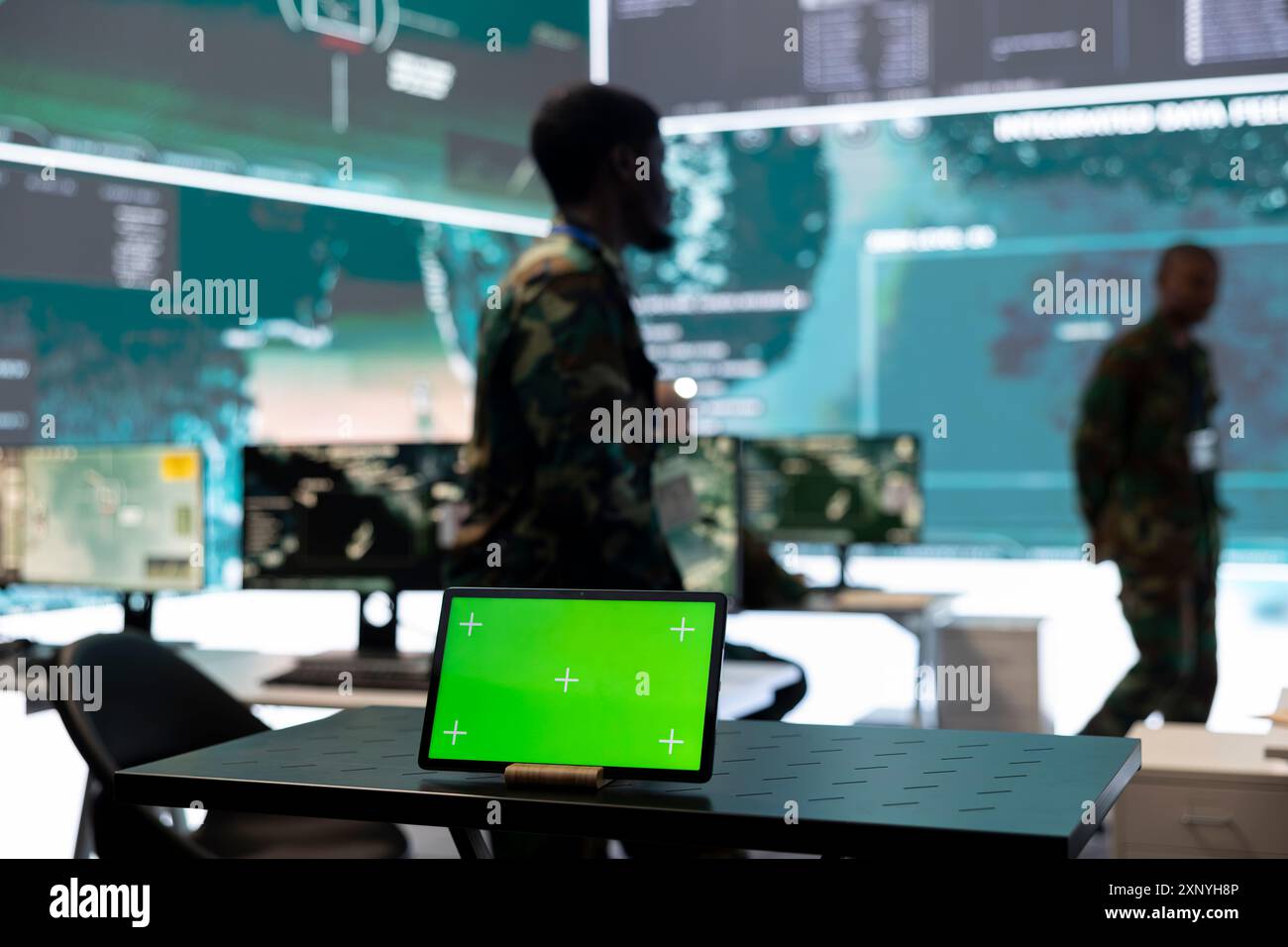 Tablet with green screen display running in a command center base of operations, army personnel ...