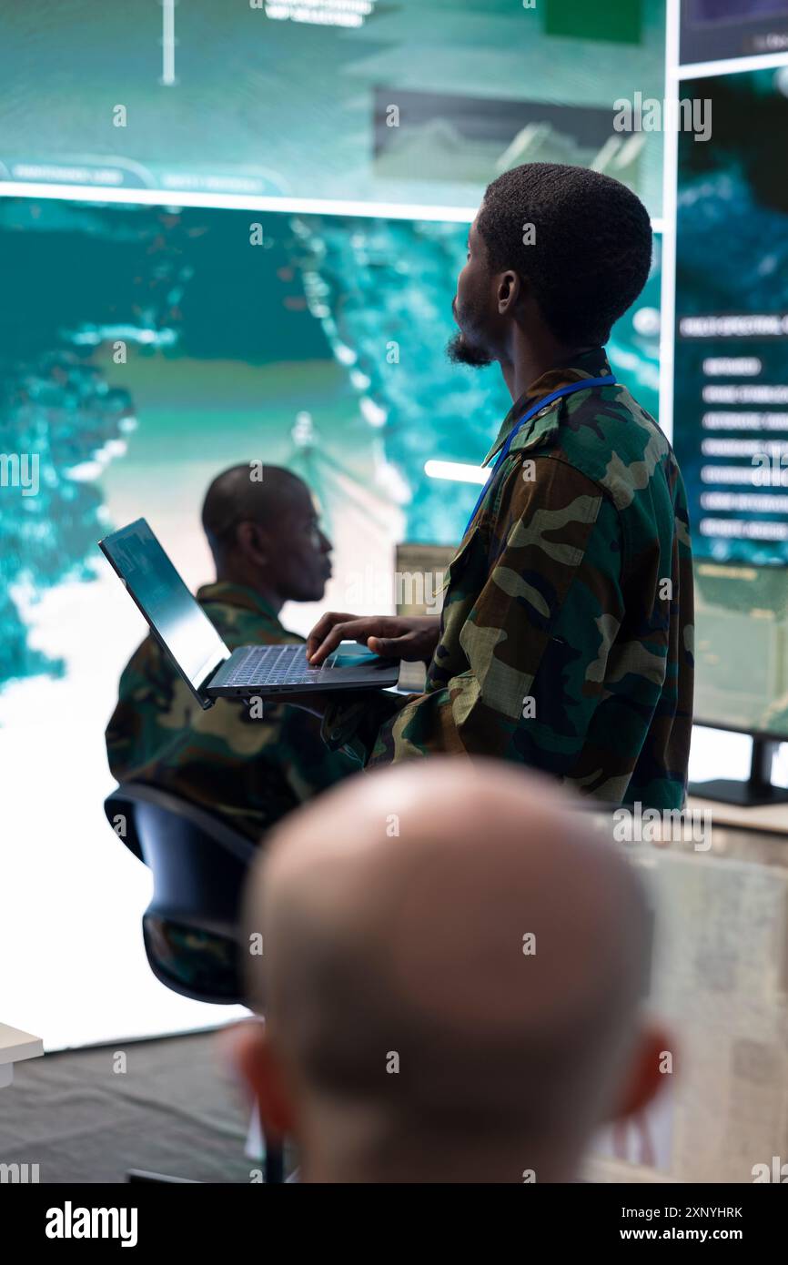 Military recruit reviewing radar surveillance footage on a big screen for reconnaissance mission ...