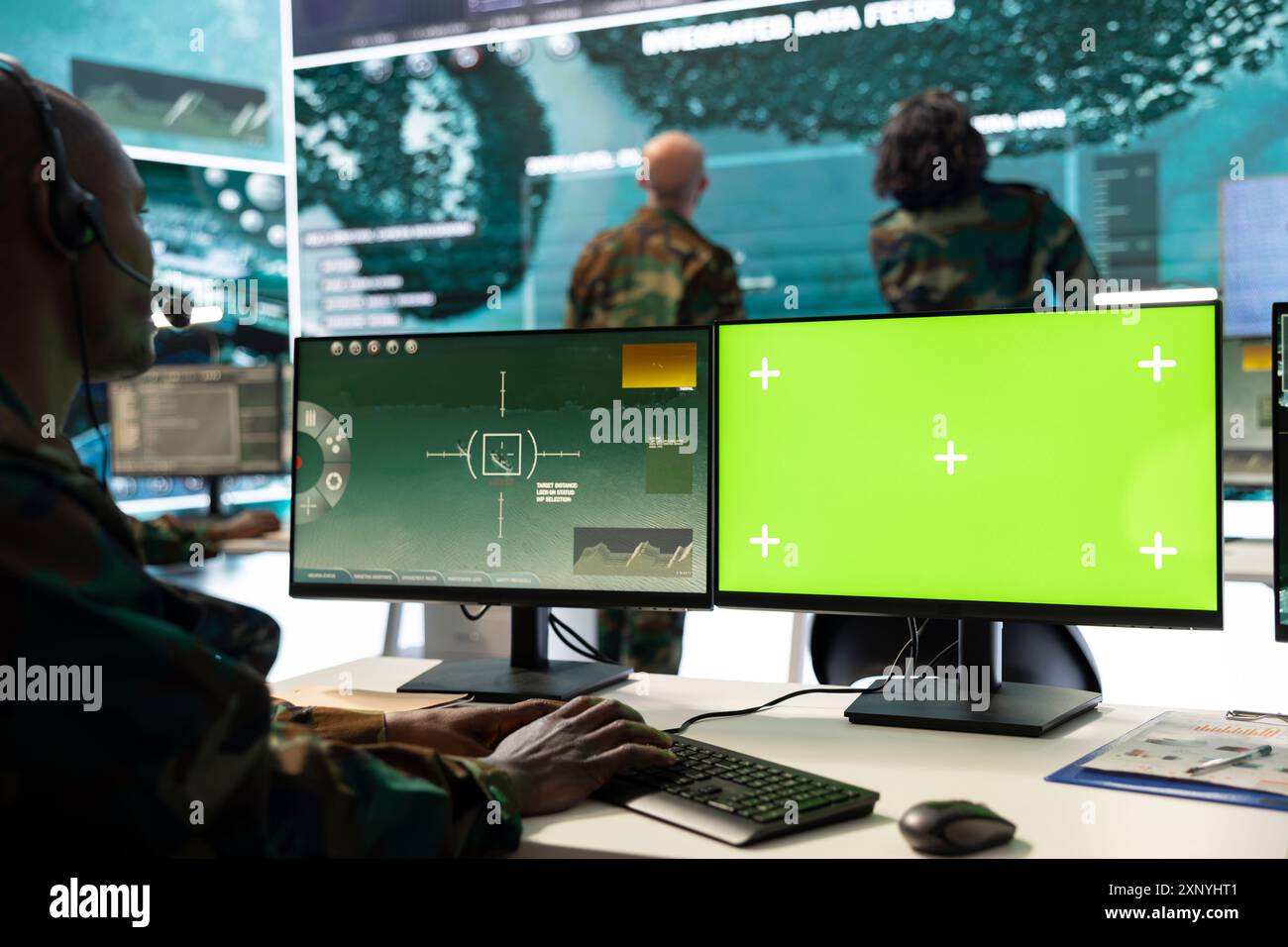 Serviceman operates on surveillance footage and green screen display ...