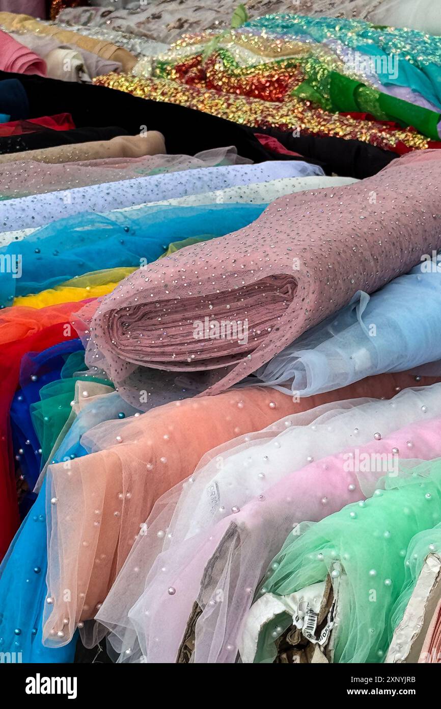 Vertical still life shows vibrant fabric bolts sitting on display in an ...