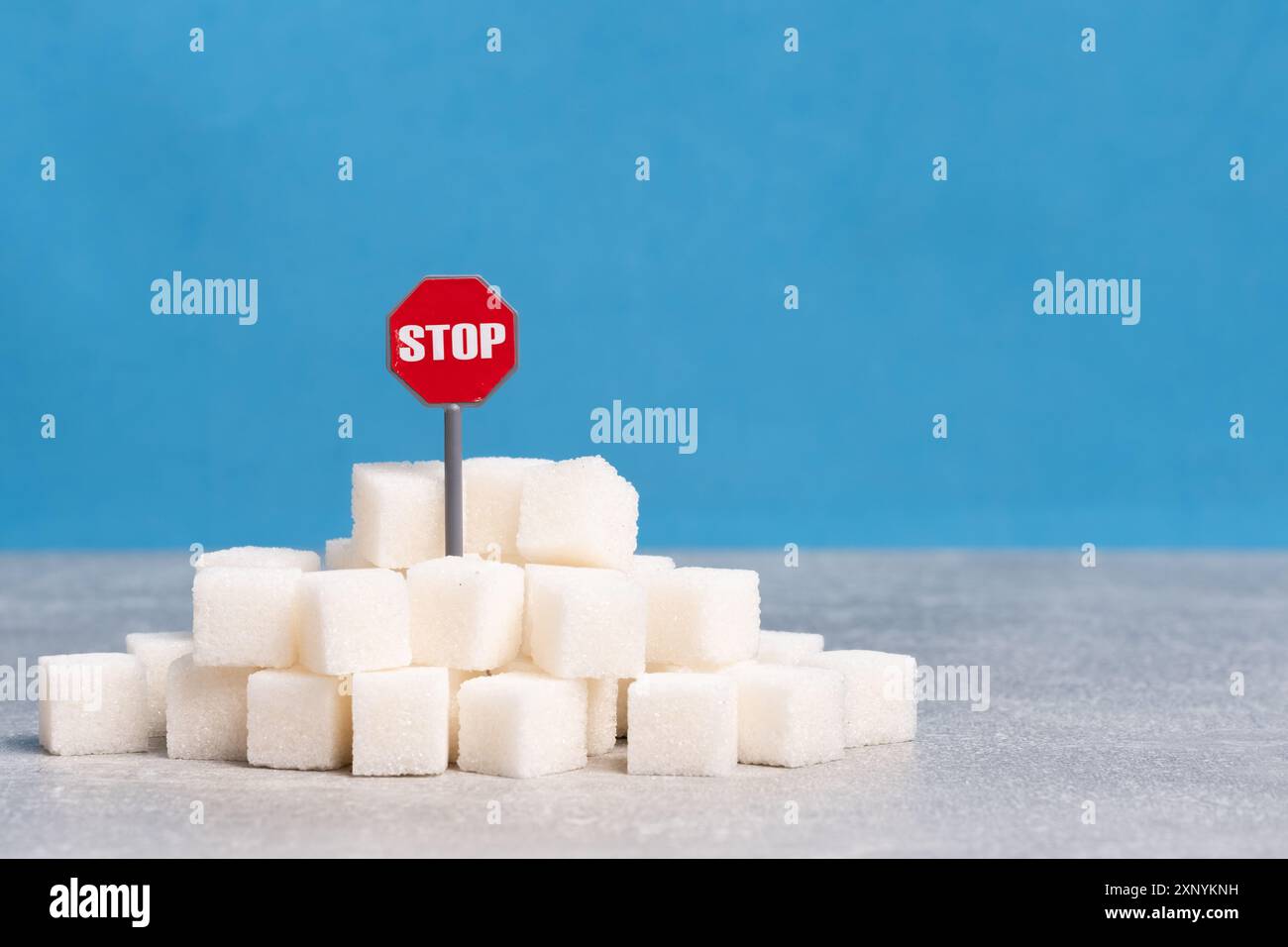 Sugar cubes and red stop sign on table against blue background Stock ...