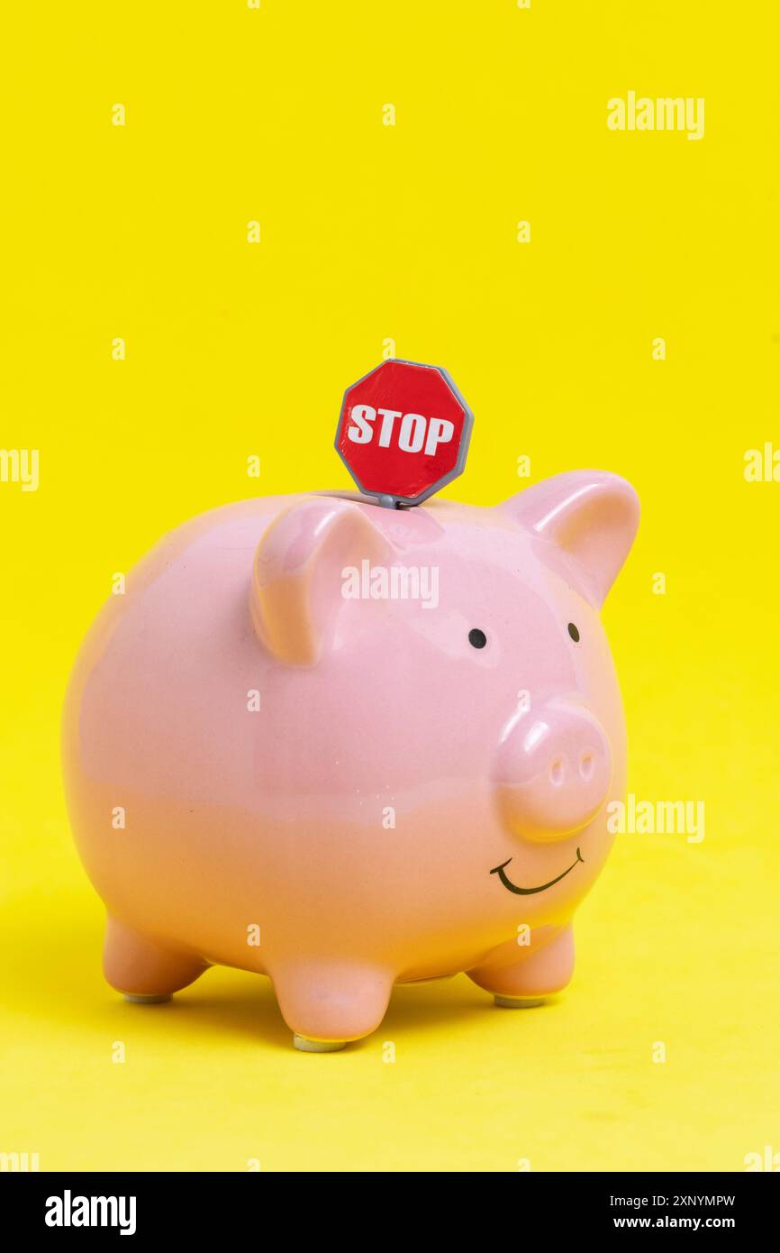 Pink piggy bank with stop sign on yellow background. Save money concept ...