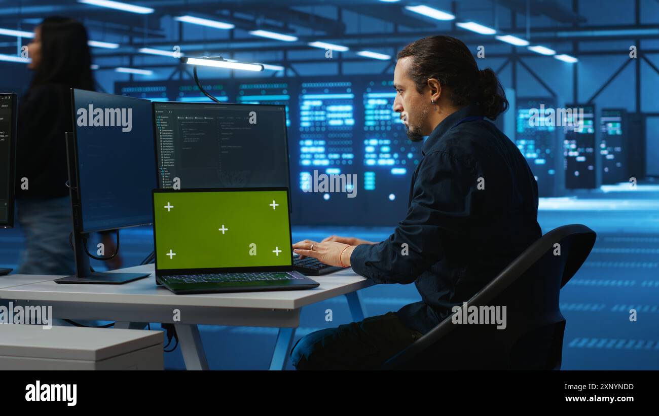 Engineer upgrading equipment in data center using green screen laptop. Specialist at PC desk in ...