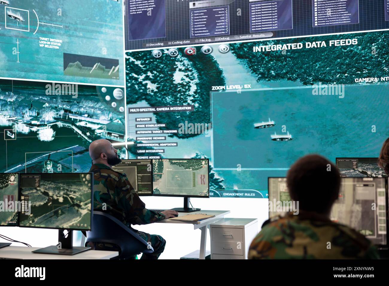 Army personnel monitoring surveillance imagery from satellite system on big screen in control ...