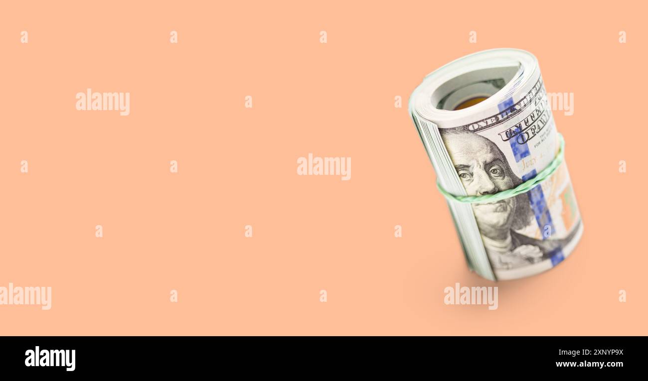 Roll Of One Hundred Dollar Bills Secured with a Rubber Band on a Peach ...