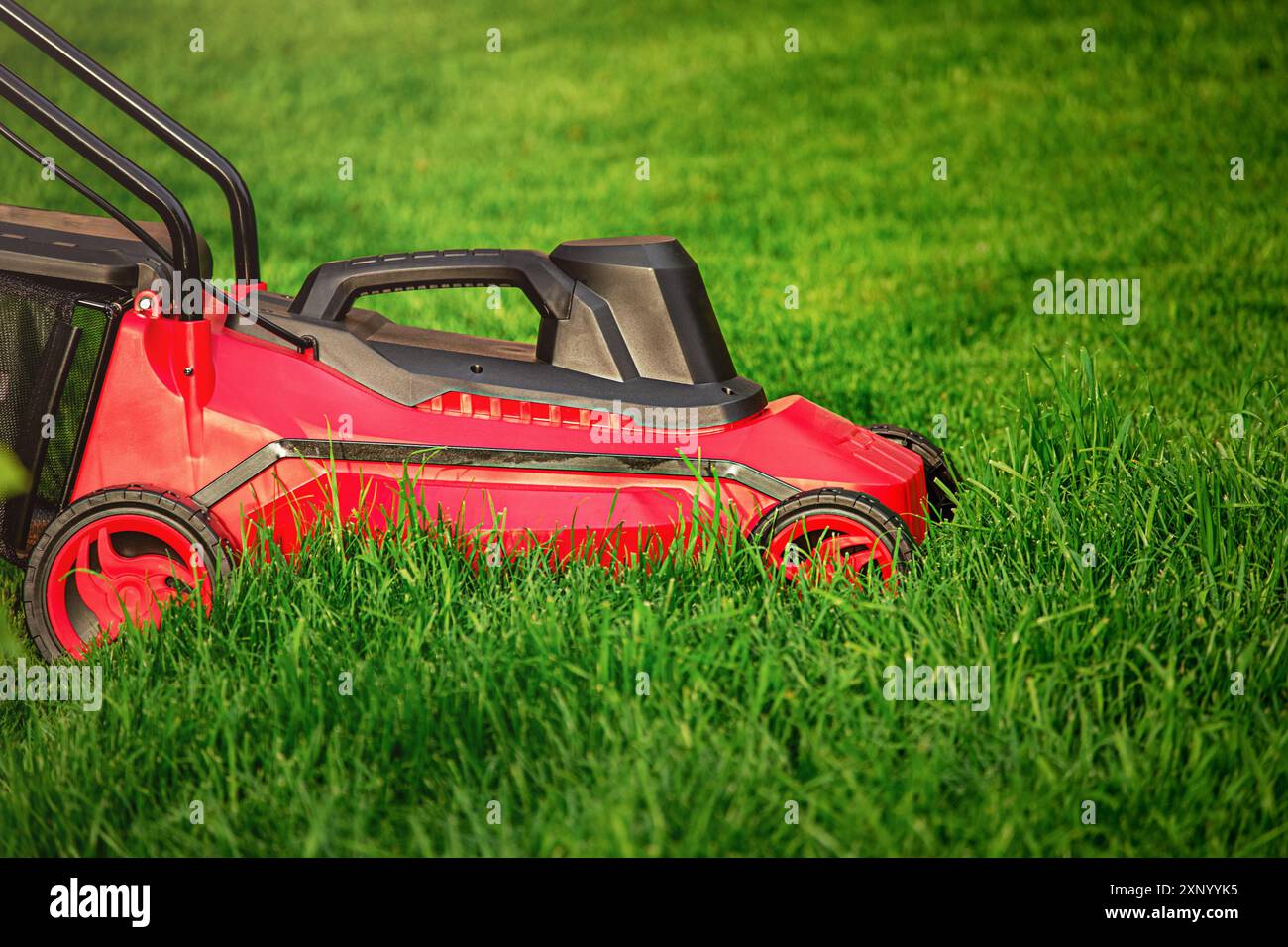 A red and black lawnmower on a background of green grass Stock Photo ...