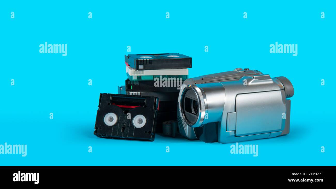 Front view of old video camera next to a black mini DV cassette tower ...
