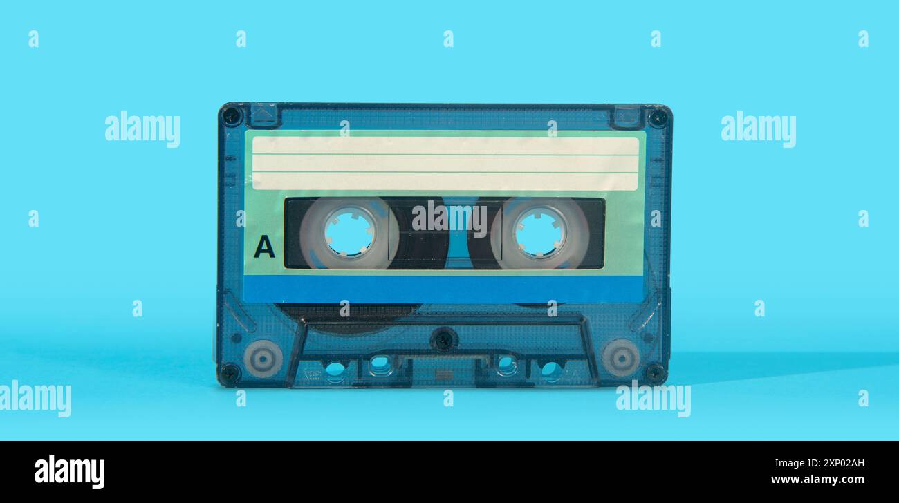 Front view of old transparent plastic music cassette on a blue surface ...