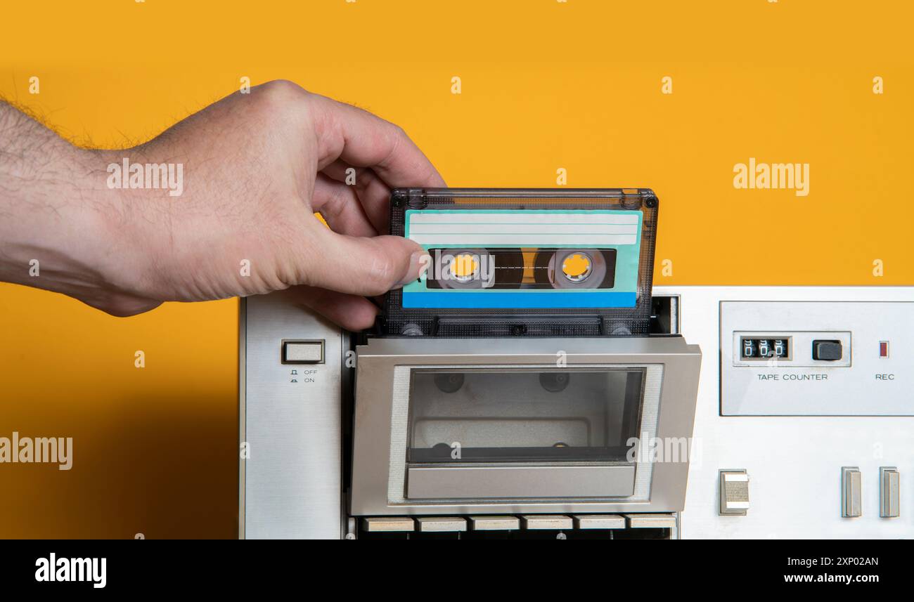 Front view of man's hand inserting old music cassette into aluminum ...