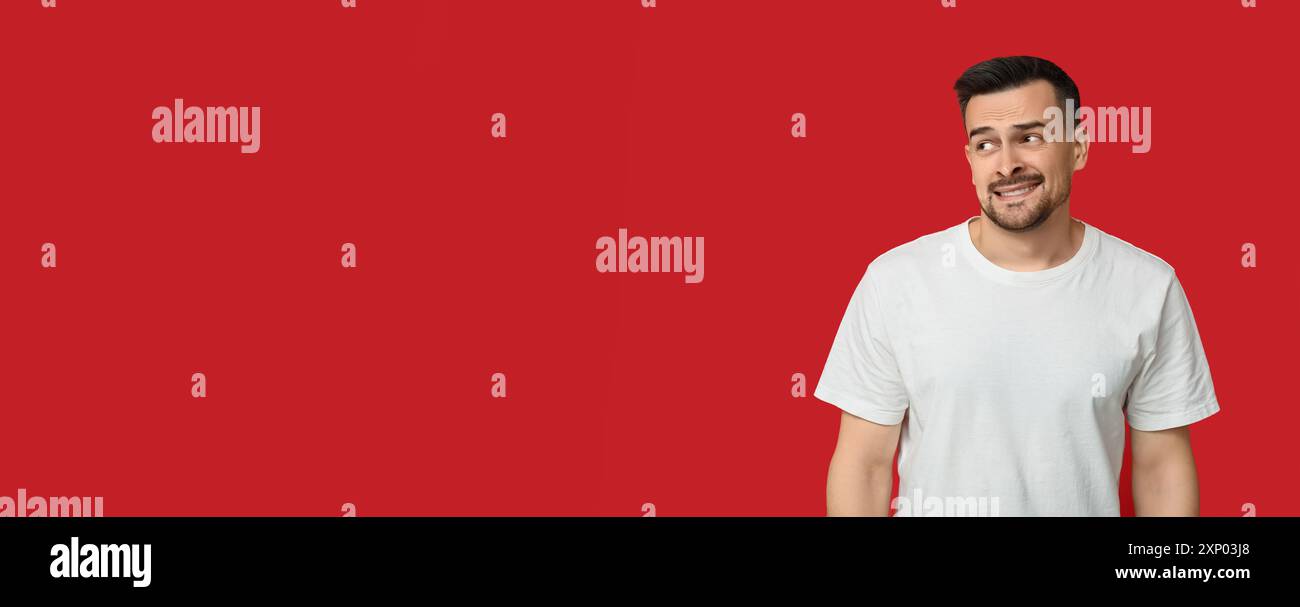 Embarrassed man on red background with space for text Stock Photo - Alamy