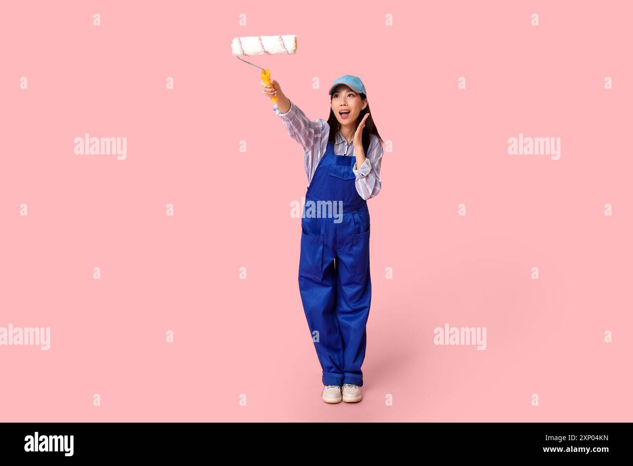 Female Asian shocked painter with roller on pink background Stock Photo ...