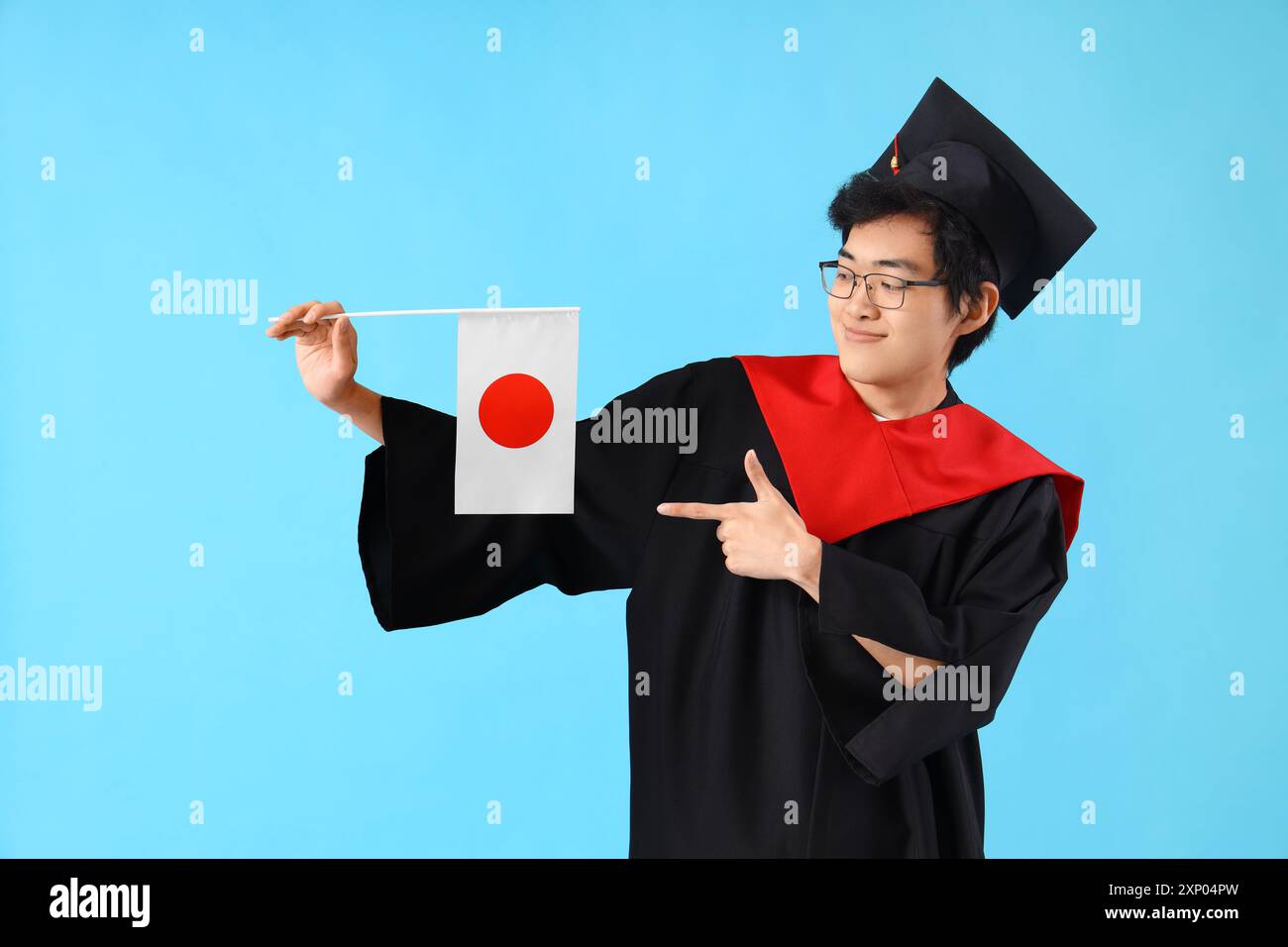 Male Asian graduate pointing at flag of Japan on blue background Stock ...