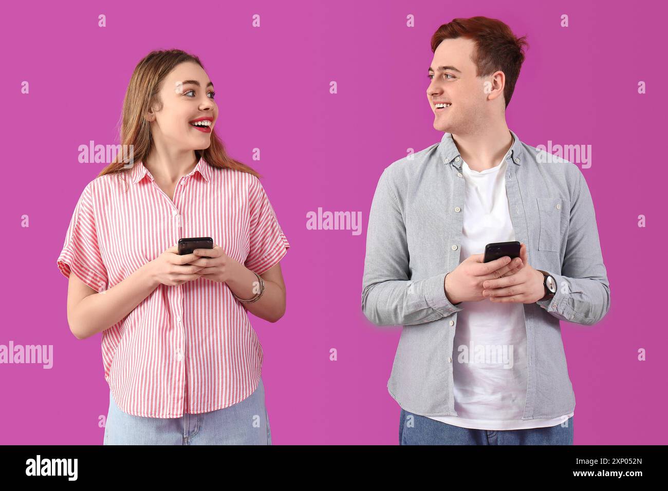 Happy young couple with mobile phones on purple background Stock Photo ...