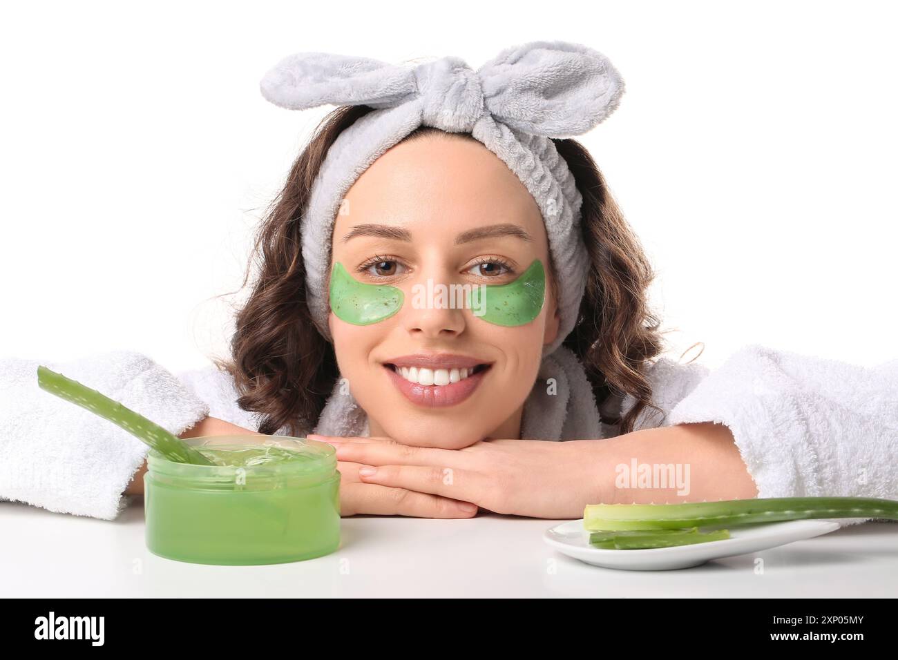 Beautiful young woman with aloe vera leaves and jar of cosmetic product ...