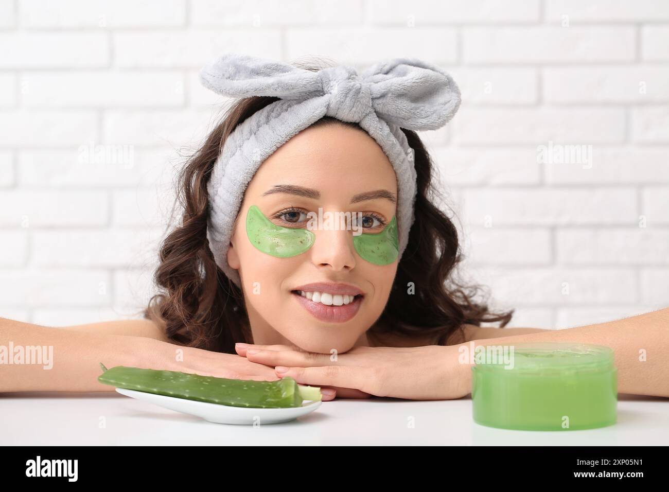 Beautiful young woman with aloe vera and jar of facial gel on white ...