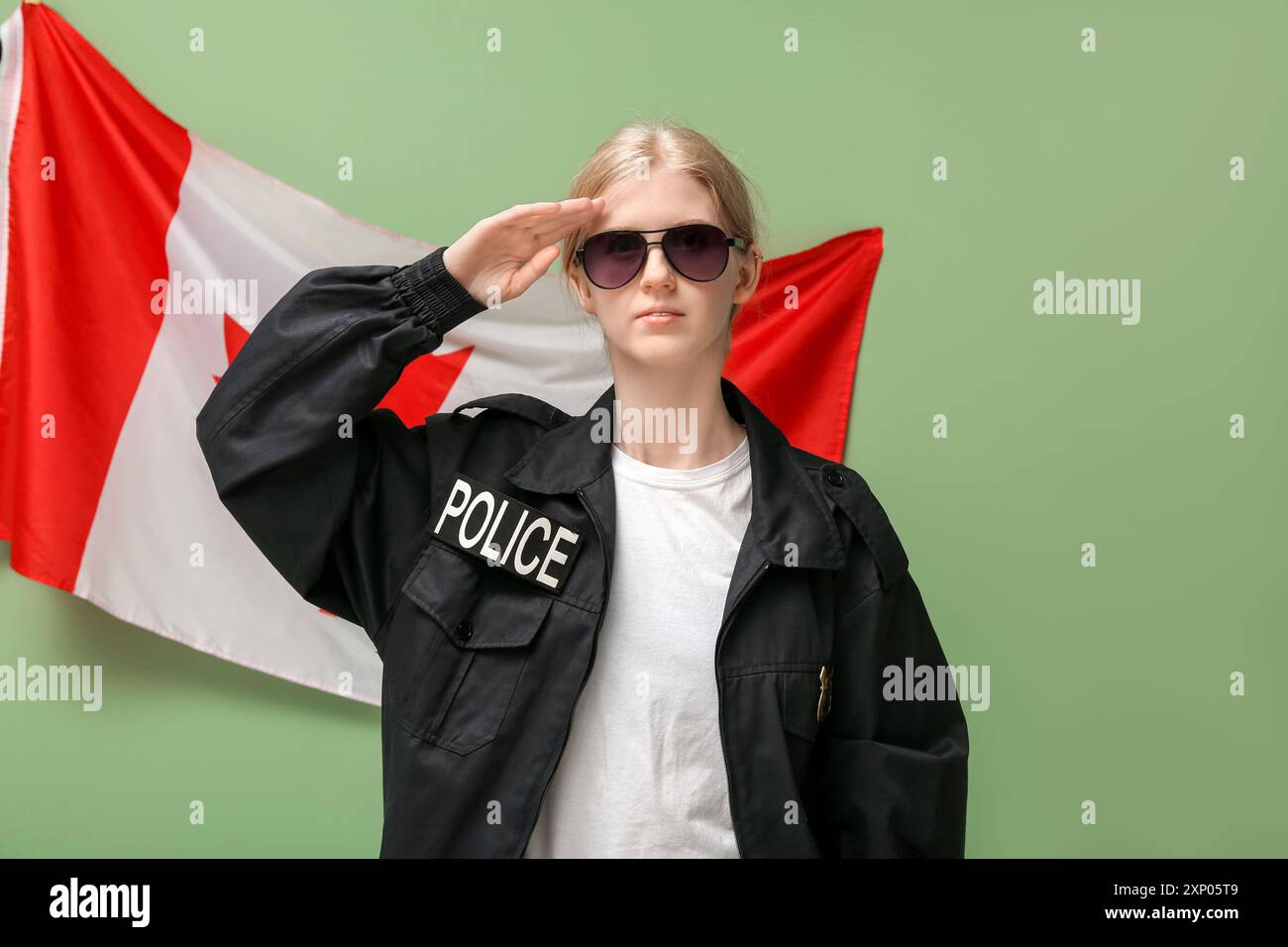Saluting female police officer and flag of Canada on green background ...