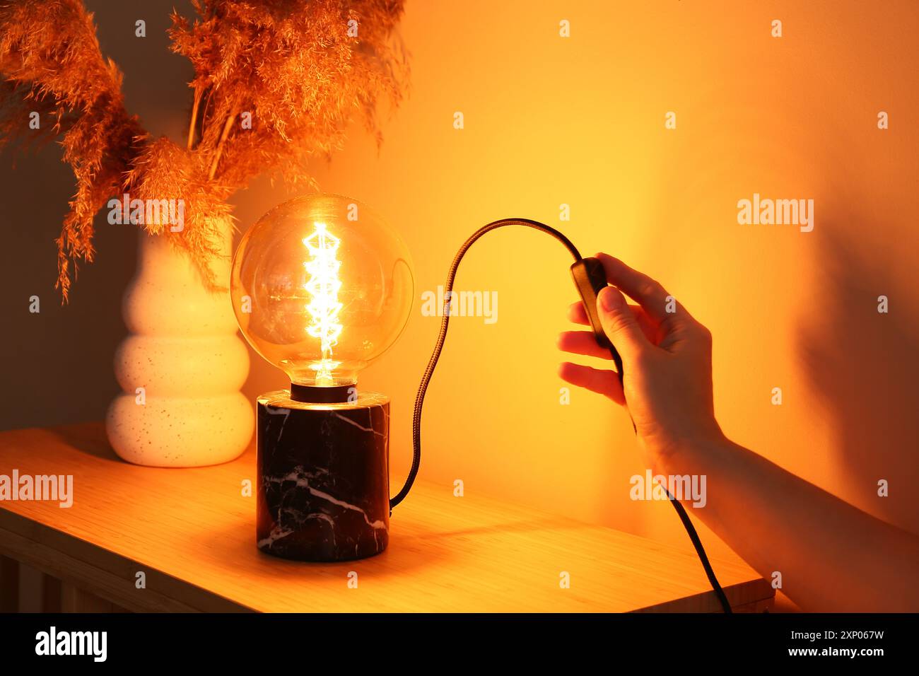 Woman turning on glowing lamp, closeup Stock Photo - Alamy